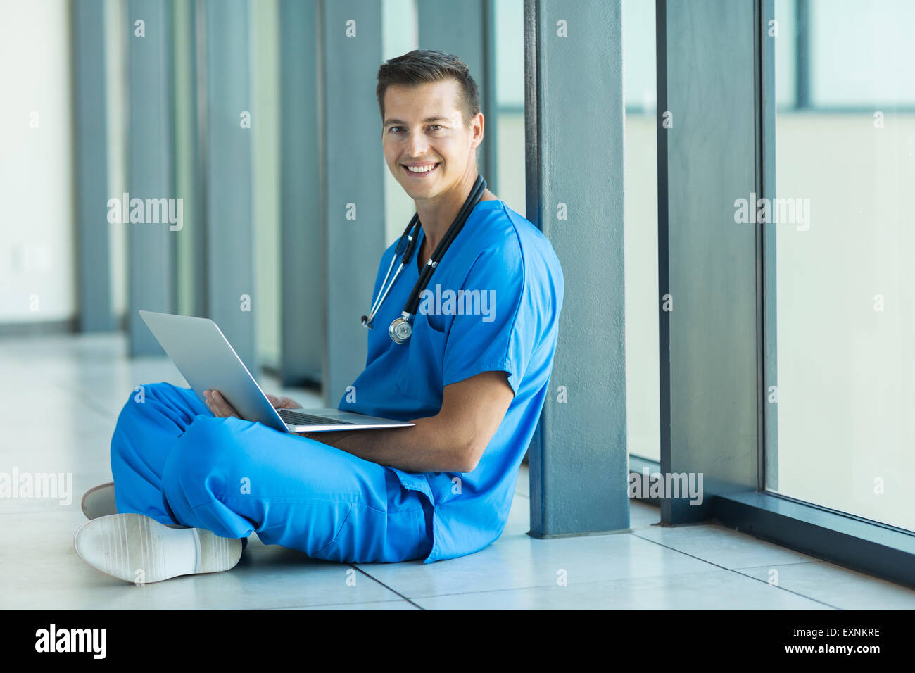 medical worker sitting on hospital floor and using laptop computer ...
