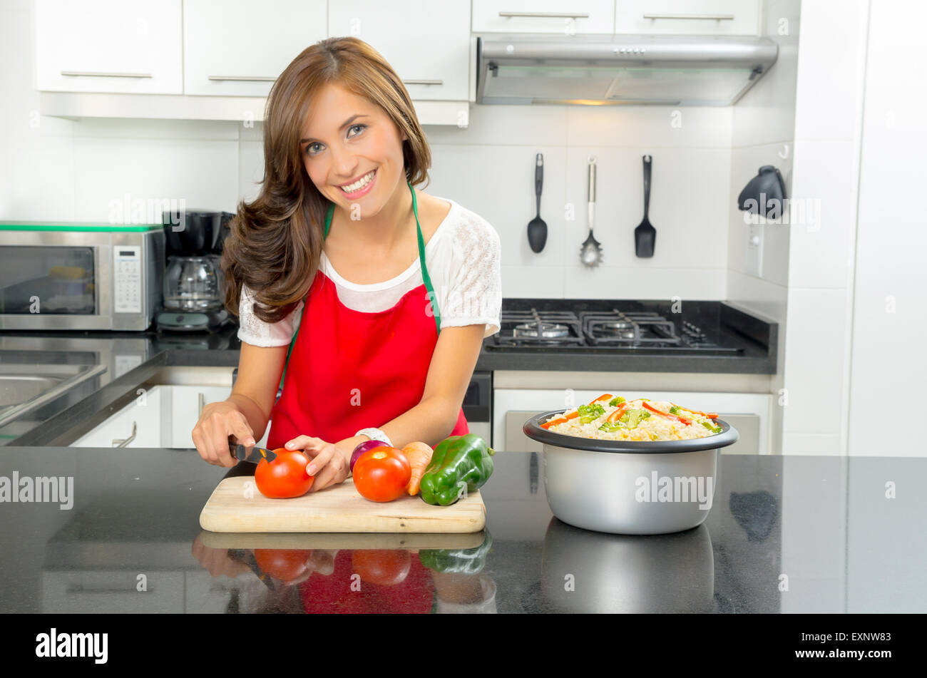 Hispanic beautiful woman cooking in modern kitchen smiling happily ...