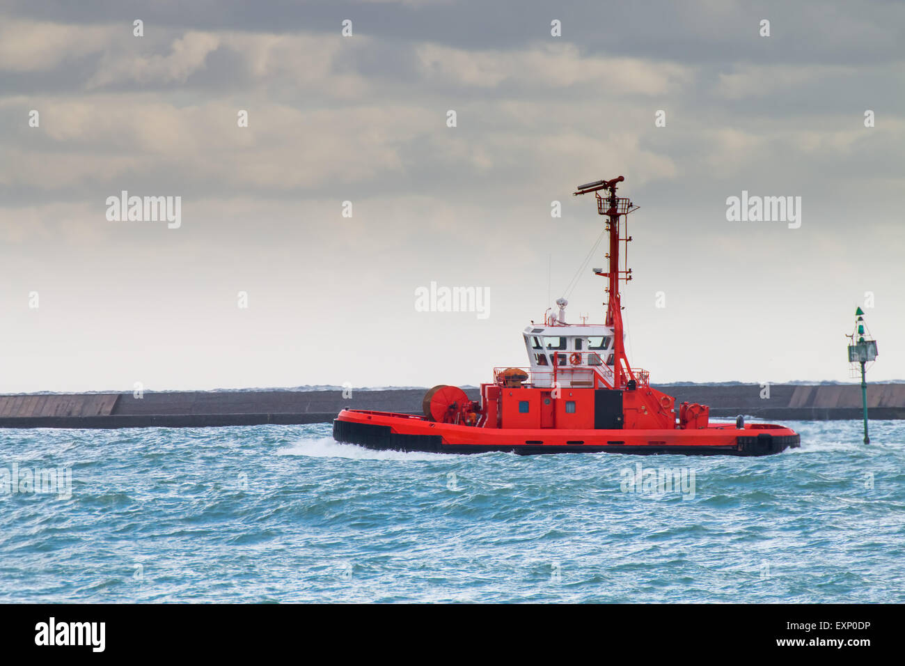 red tugboat navigates in port in a cloudy day waiting for a ship Stock ...