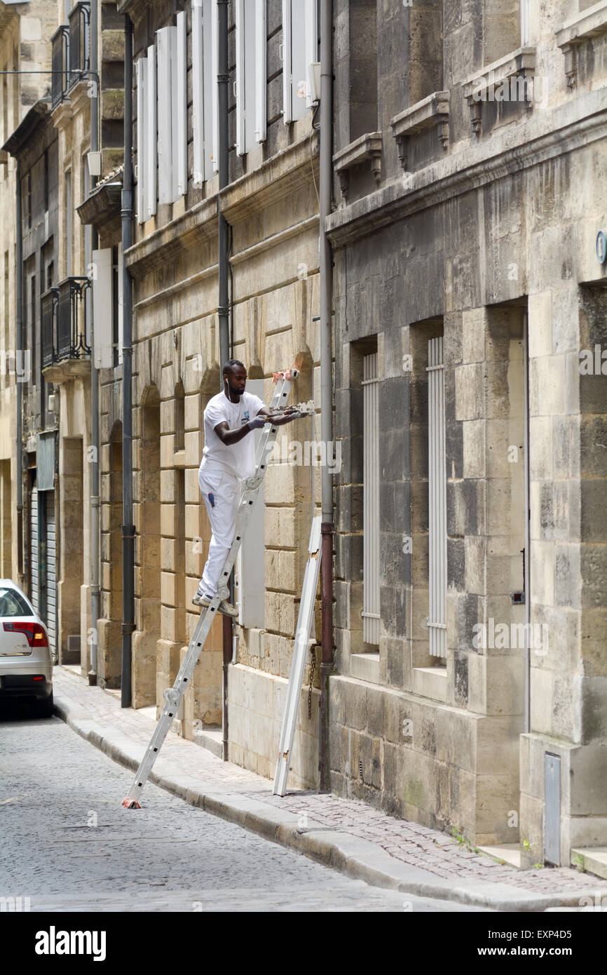 Man on ladder repairing window shutters outside house in Bordeaux ...