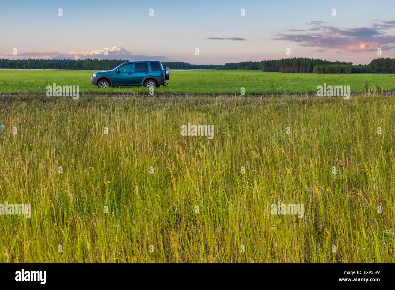 Rural grassland landscape with green off-road car. Beautiful rural ...
