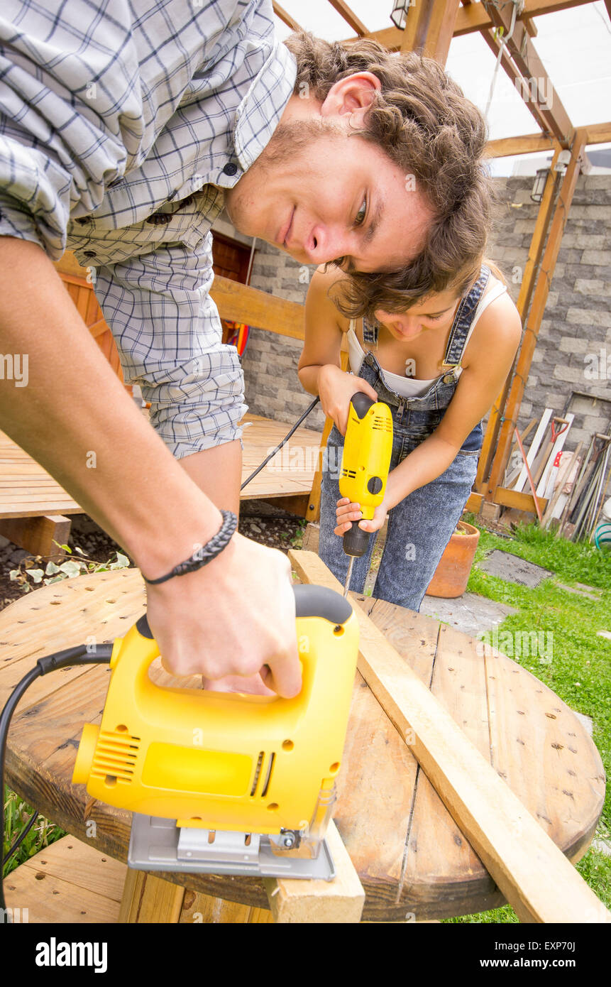 Couple working together on renovation project outdoors using a jigsaw ...