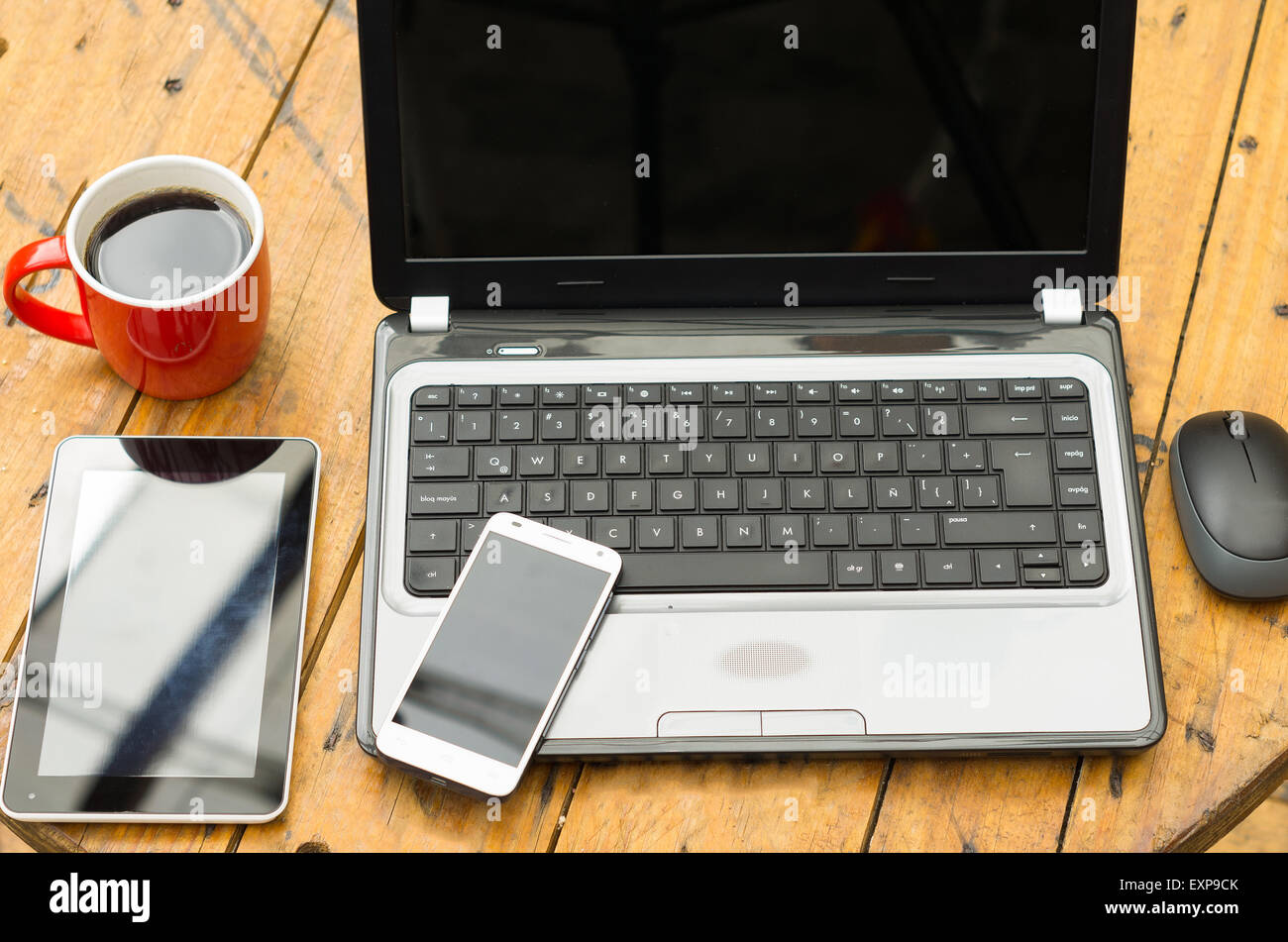 Wooden table with open laptop, mobile, tablet and red coffee mug Stock ...