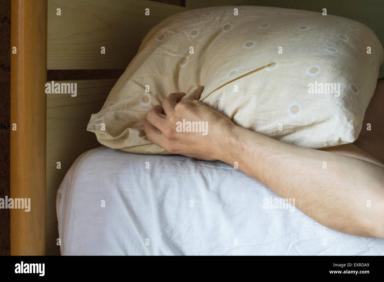 Young man on the bed with a cushion over his head Stock Photo - Alamy