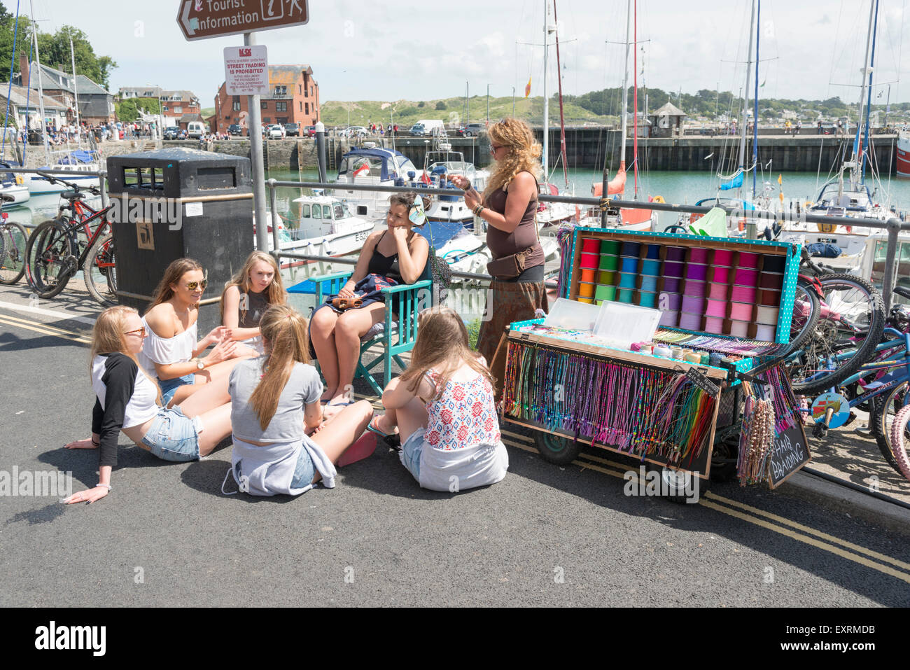 A street trader selling hair braids and braiding to young girls on the ...