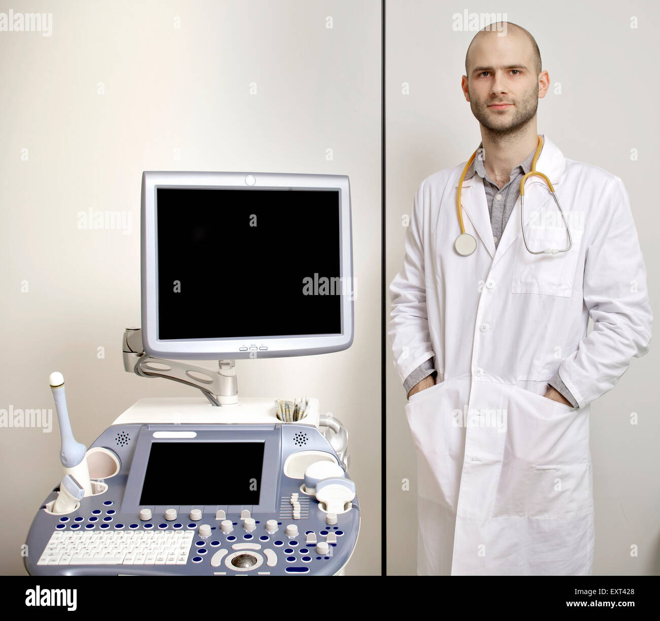 Portrait of young male technician operating ultrasound machine in white ...