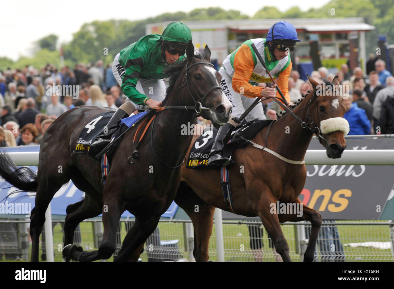 Horses and jockeys racing. Stands and spectators in the background ...
