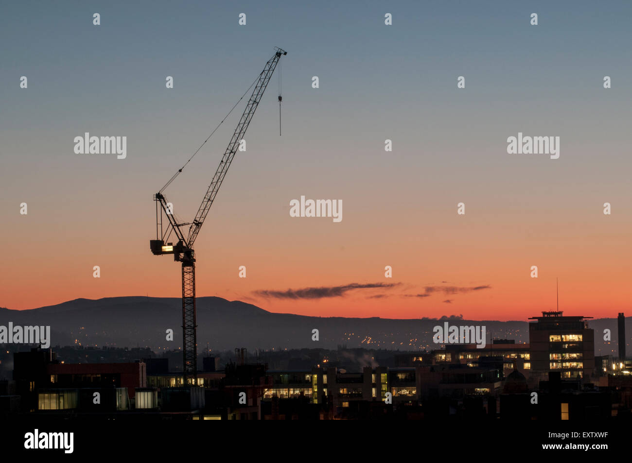 A Crane looks over Edinburgh capital of Scotland at sunset in November ...