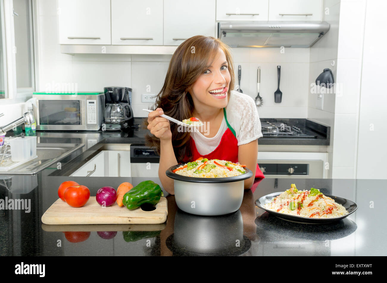 Hispanic beautiful woman cooking in modern kitchen bending over counter ...
