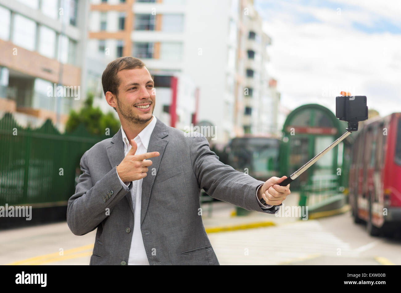 Man wearing formal clothing posing with selfie stick in urban ...