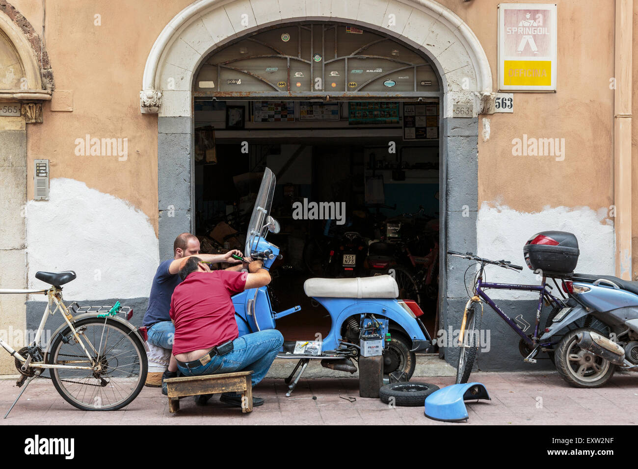 Two mechanics repairing a motorcycle, Giardini Naxos, Sicily, Italy ...