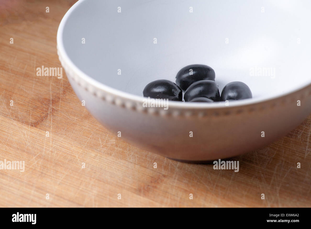 Bowl with some black olives side view. Copyspace on the wooden plate ...