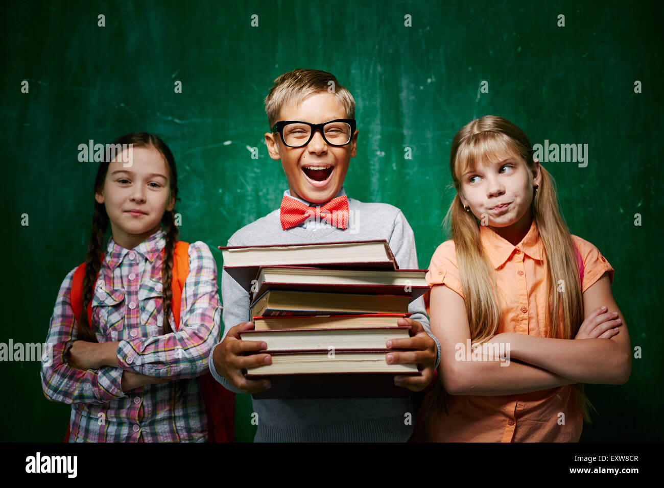 Ecstatic pupil with books standing between two schoolmates Stock Photo ...