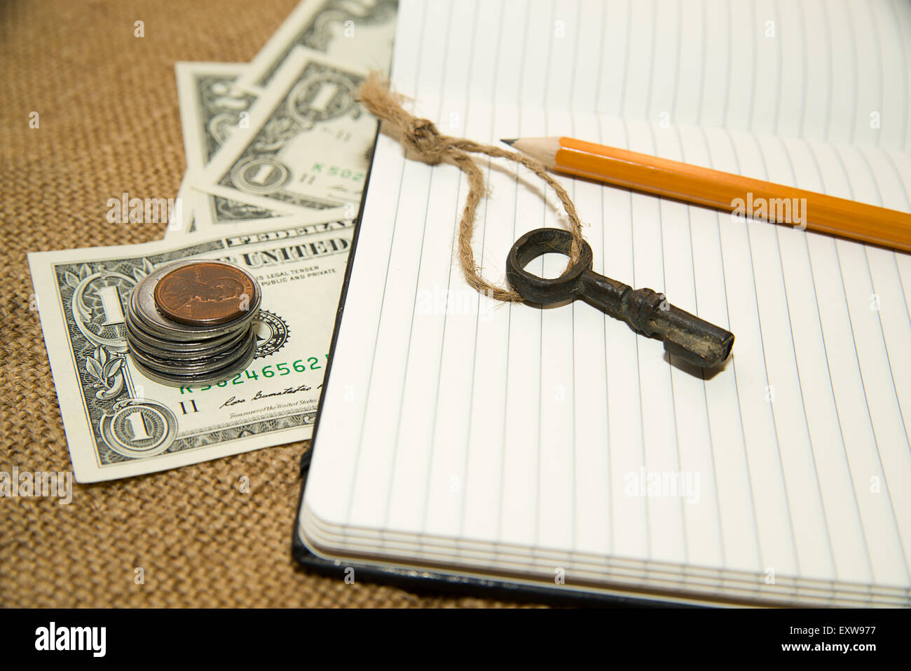Opened notebook with a blank sheet, pencil, key and money on the old ...