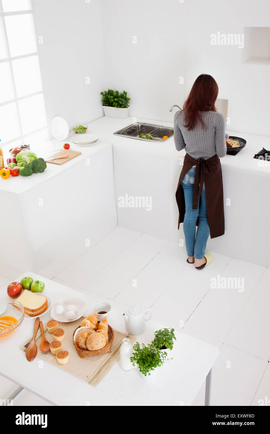 Young woman standing in the kitchen with rear view Stock Photo - Alamy