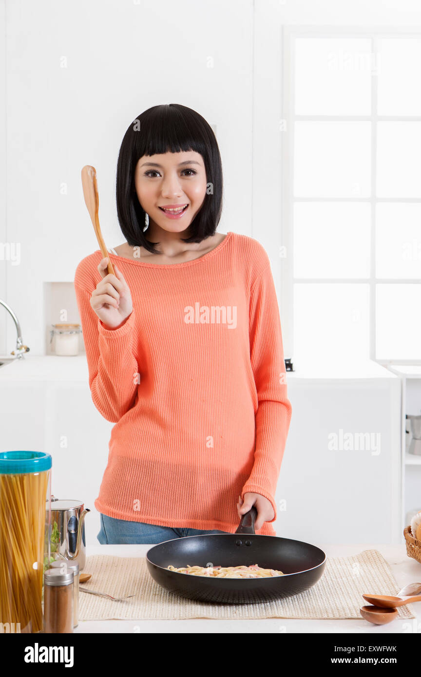 Young woman holding a pan and ladle with smile Stock Photo - Alamy