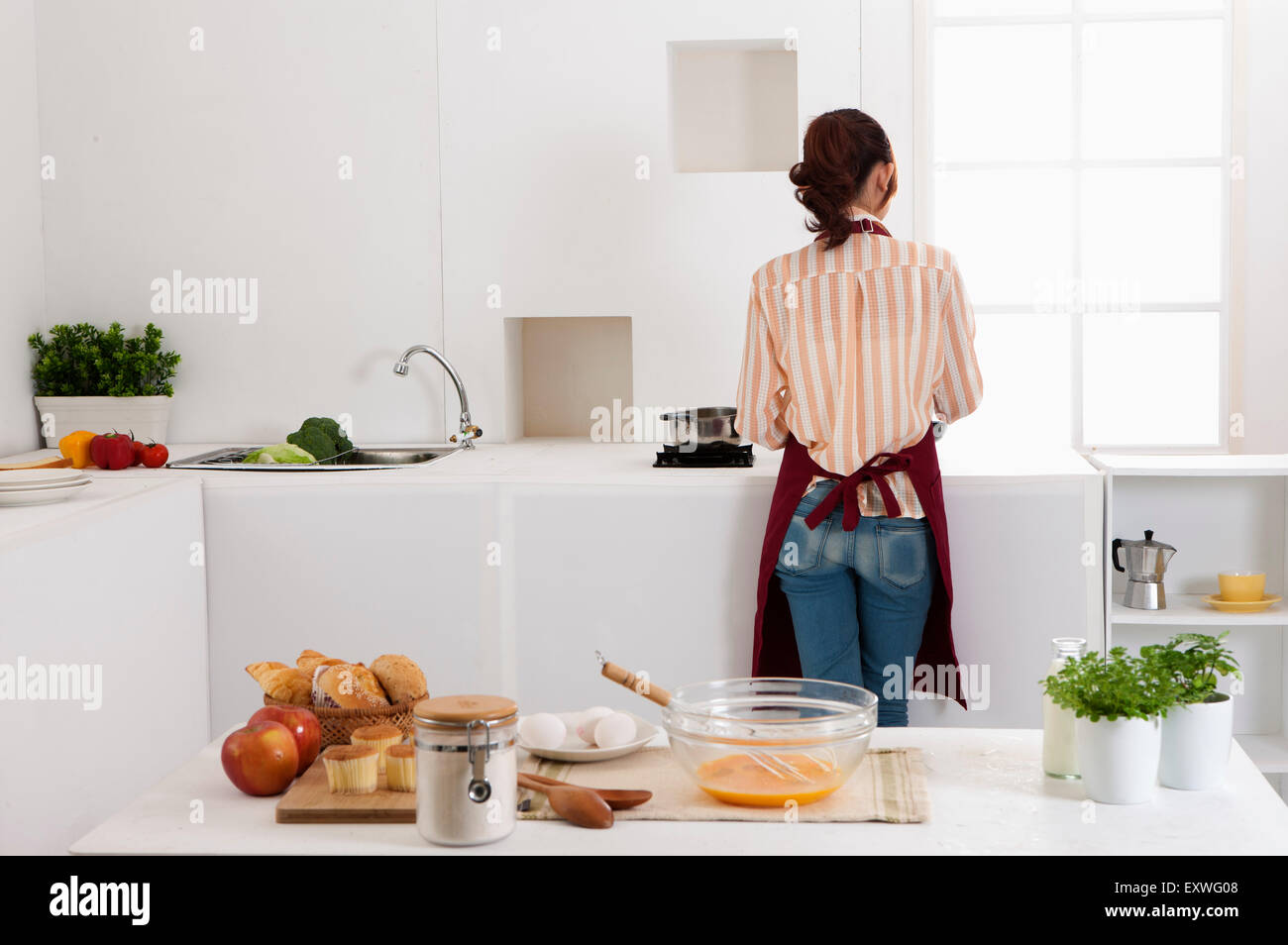 Young woman standing in the kitchen with rear view Stock Photo - Alamy