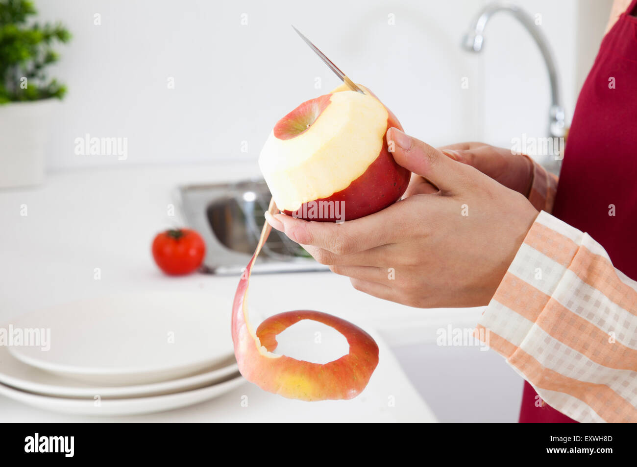 Young woman peeling an apple in the kitchen Stock Photo - Alamy