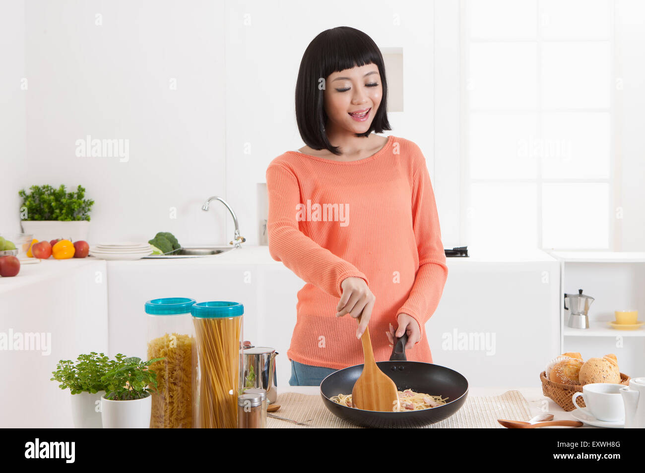 Young woman cooking in the kitchen with smile Stock Photo - Alamy