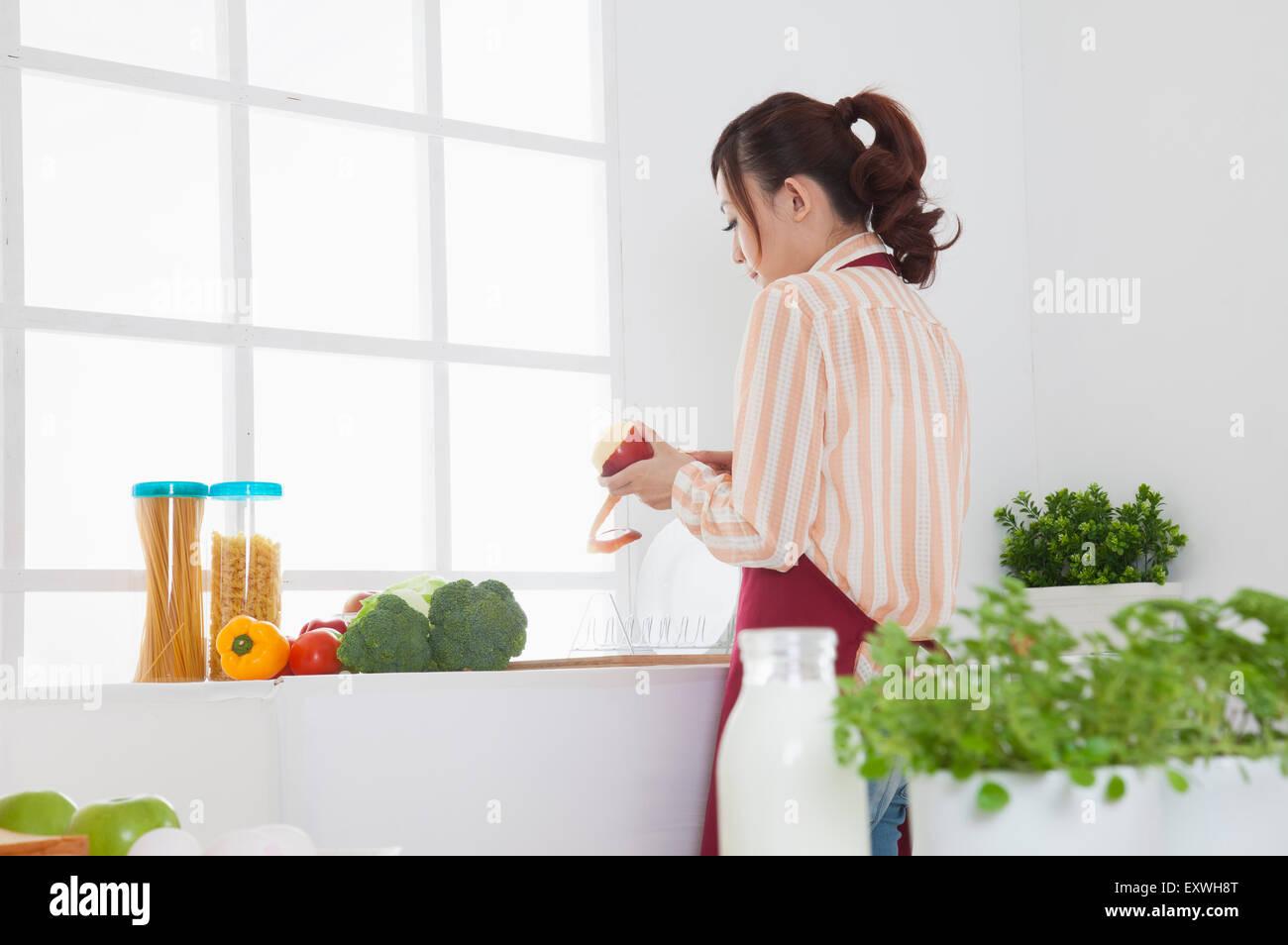 Young woman peeling an apple in the kitchen Stock Photo - Alamy