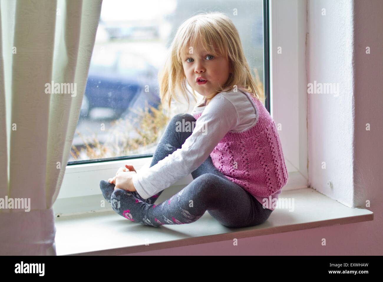Girl sitting on window sill Stock Photo - Alamy