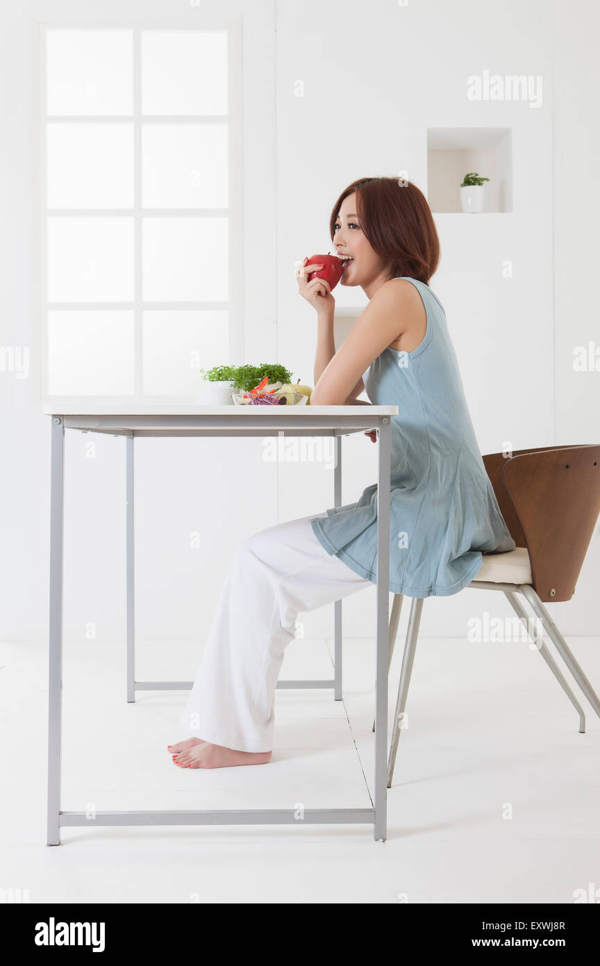 Young woman eating apple and looking away with smile Stock Photo - Alamy