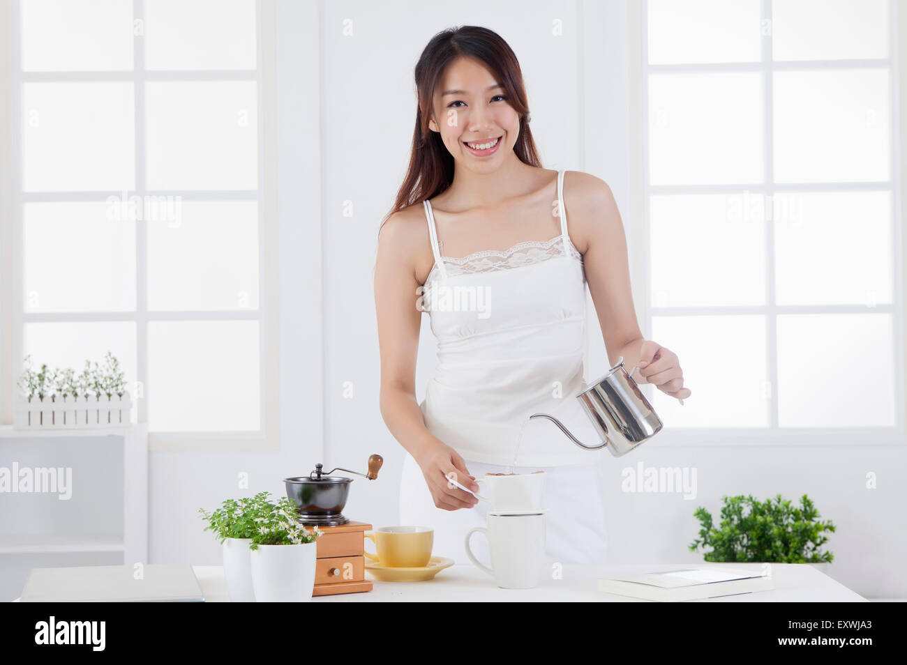 Young woman holding teapot and smiling at the camera Stock Photo - Alamy