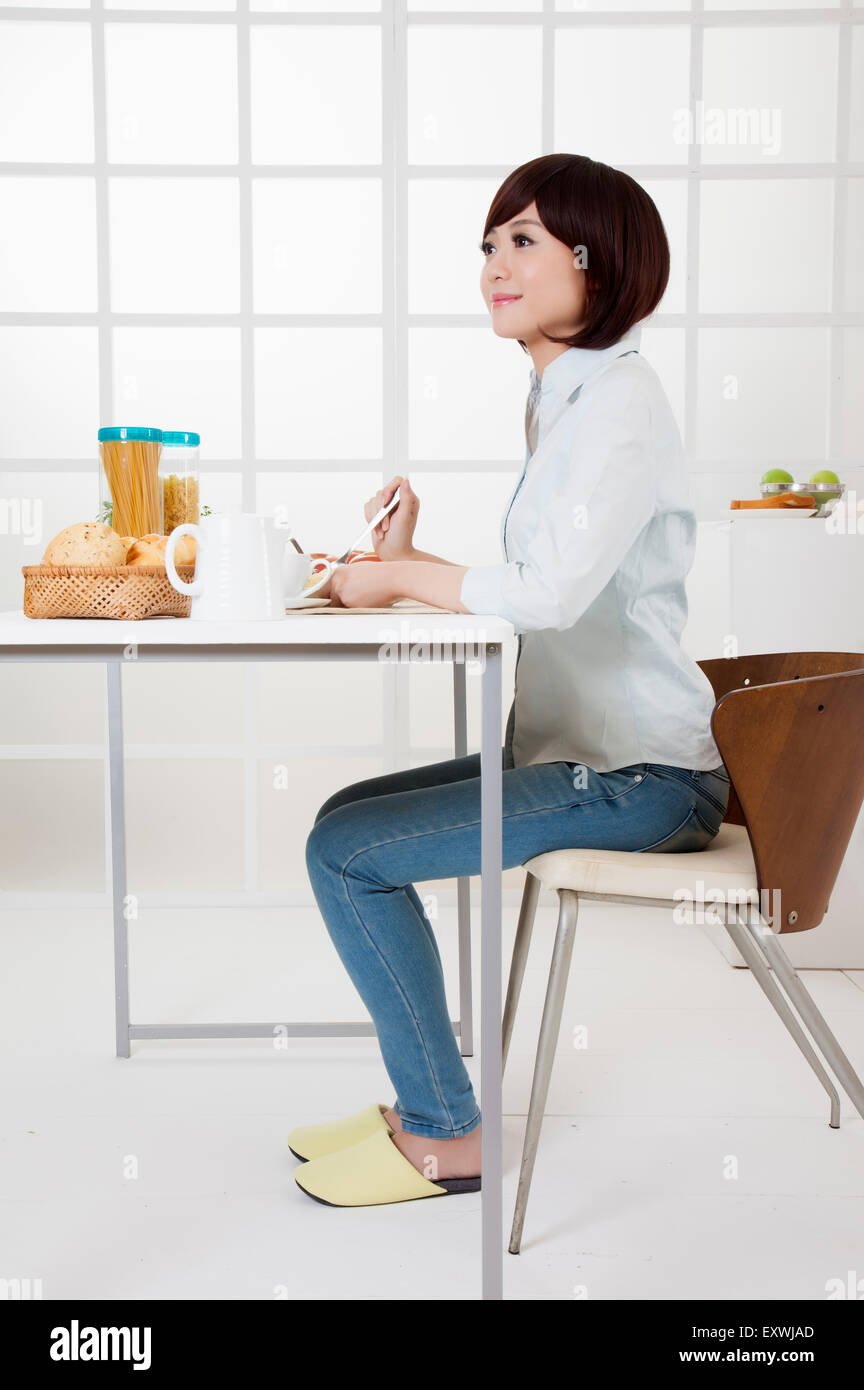 Young woman sitting and eating breakfast with smile Stock Photo - Alamy