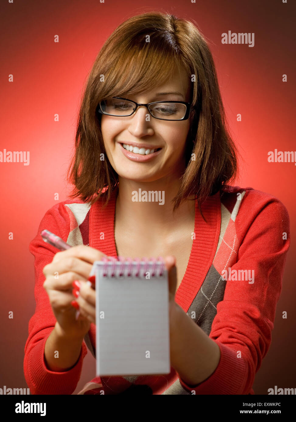 Beautiful smiling woman writing something in her notebook Stock Photo ...
