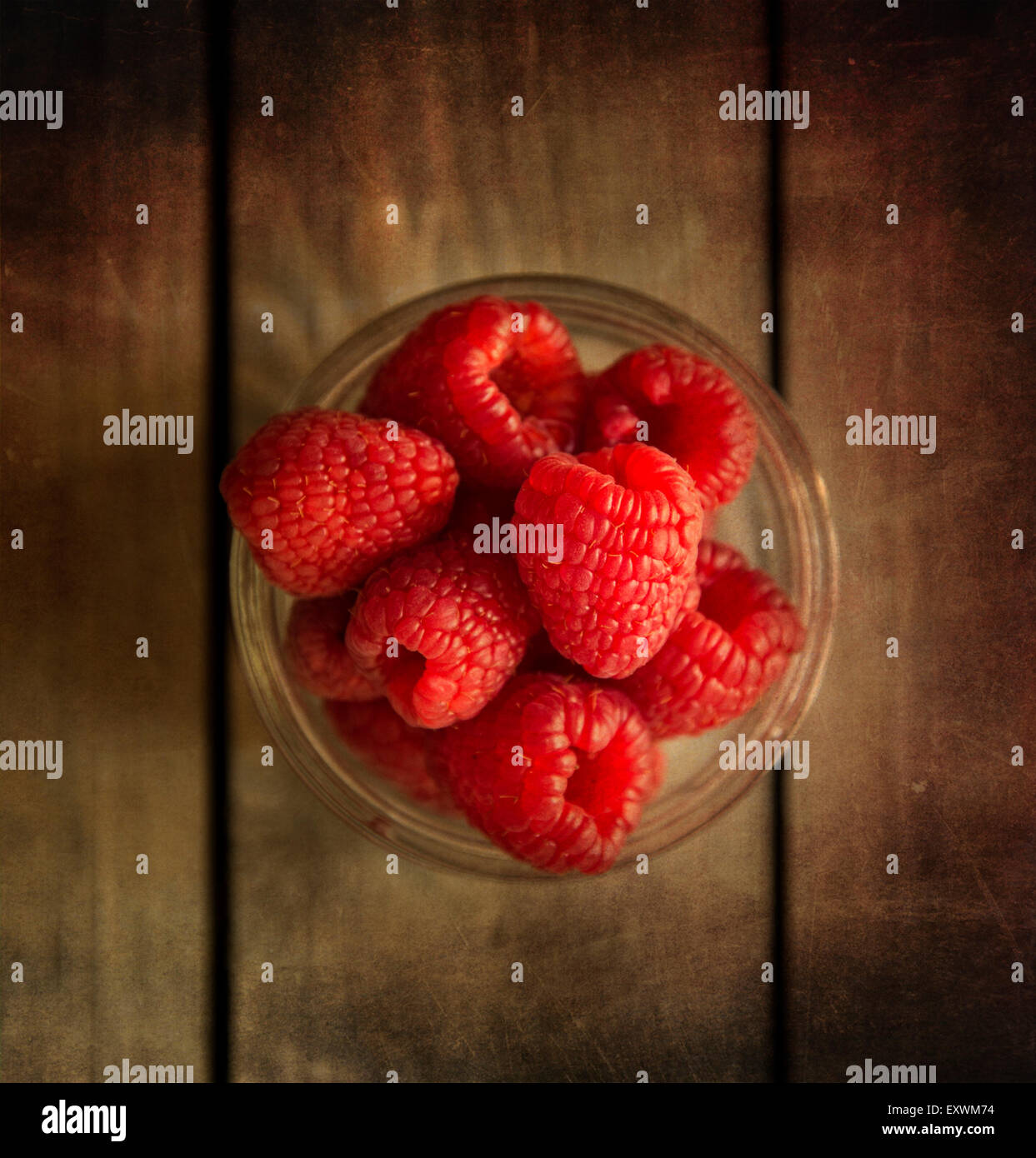 Raspberries in rustic setting with wooden background with added texture ...