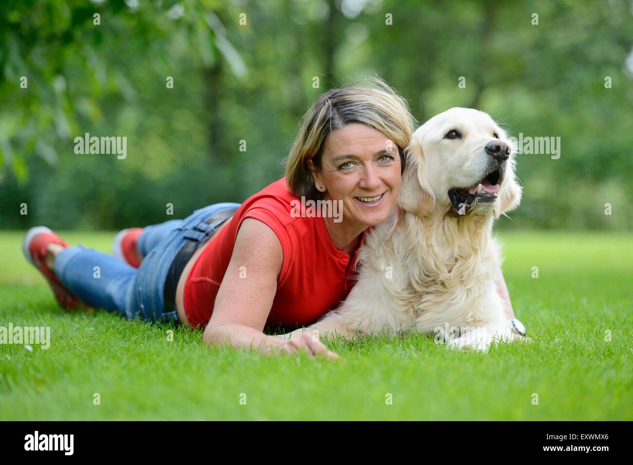 Mature woman with a golden retriever in garden Stock Photo - Alamy