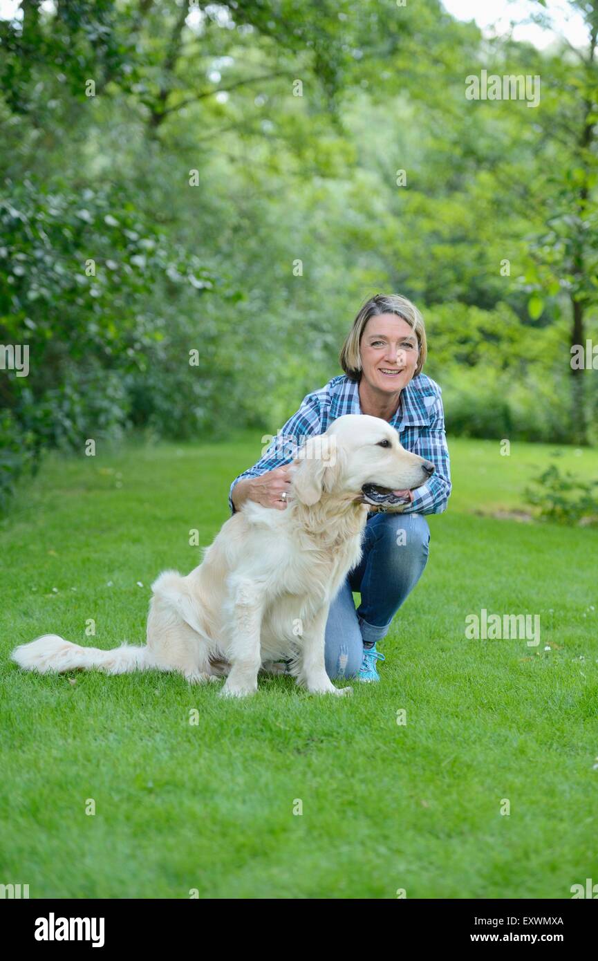 Mature woman with a golden retriever in garden Stock Photo - Alamy
