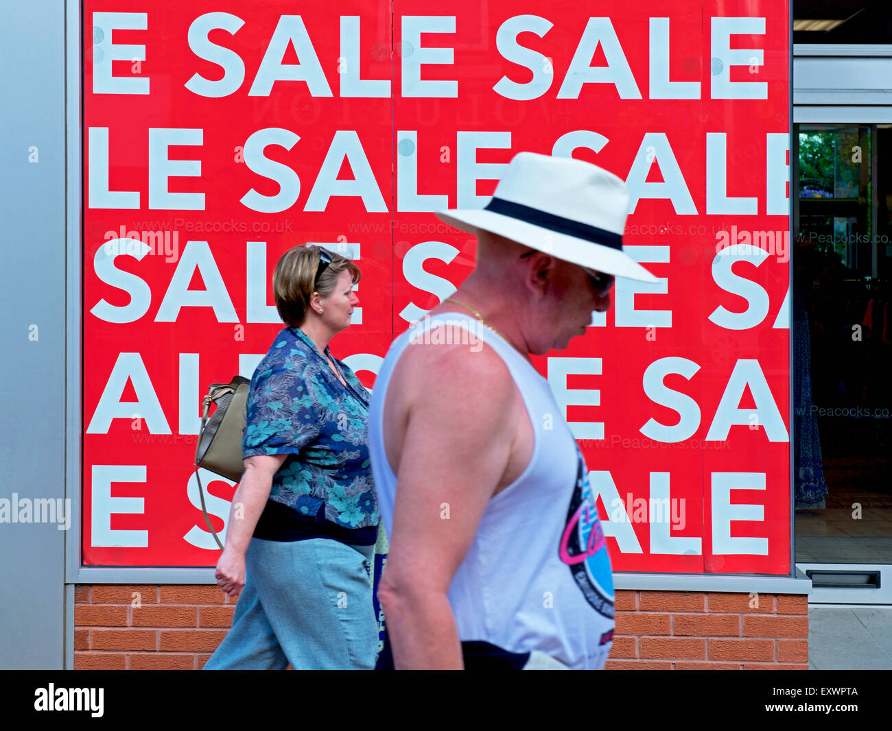 Man and woman walking past shop window, with sale sign, England UK ...