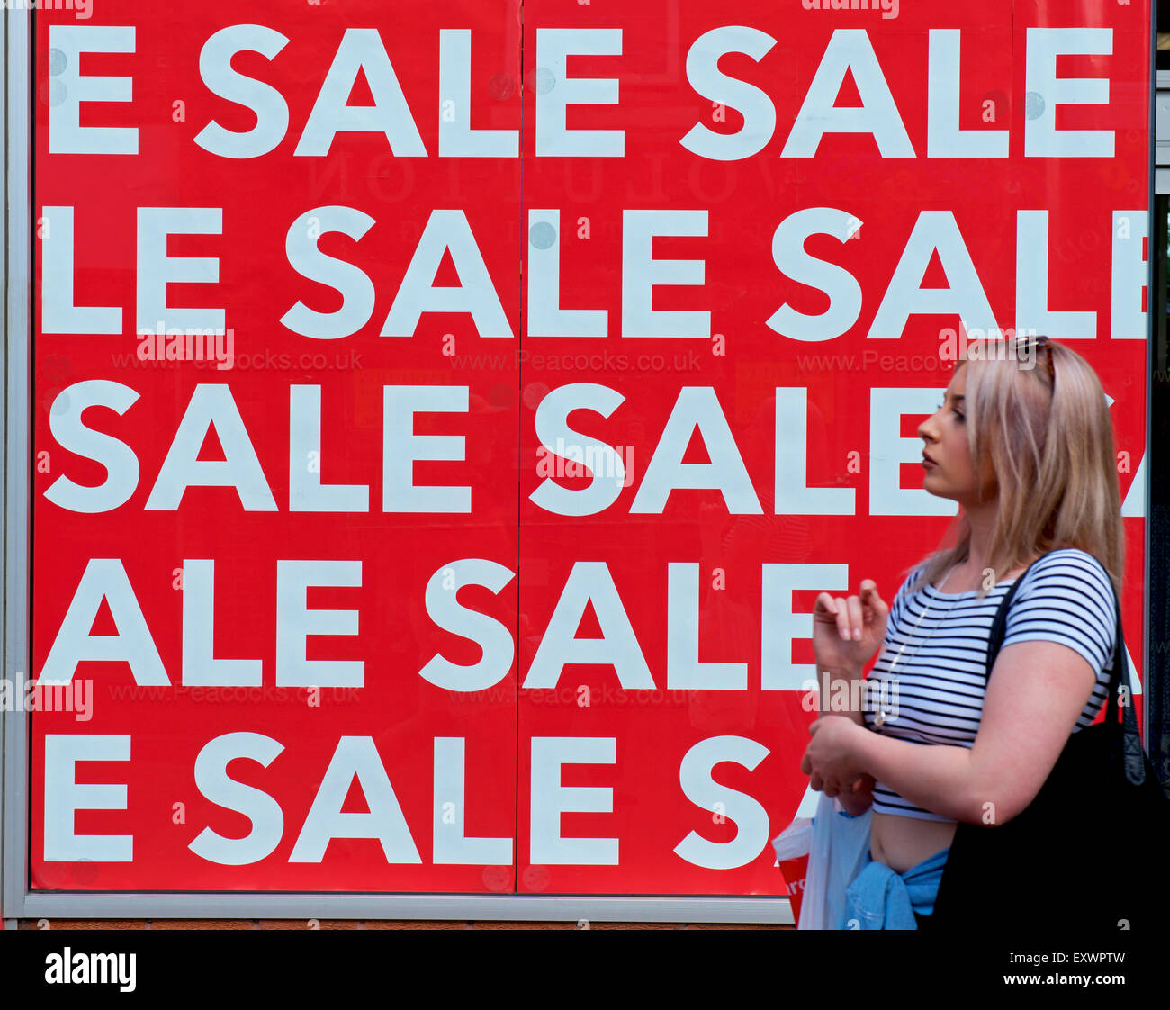 Young woman walking past shop window, with sale sign, England UK Stock ...