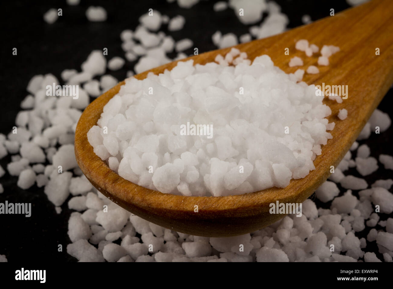 Sea salt In wooden spoon on dark stone background Stock Photo - Alamy