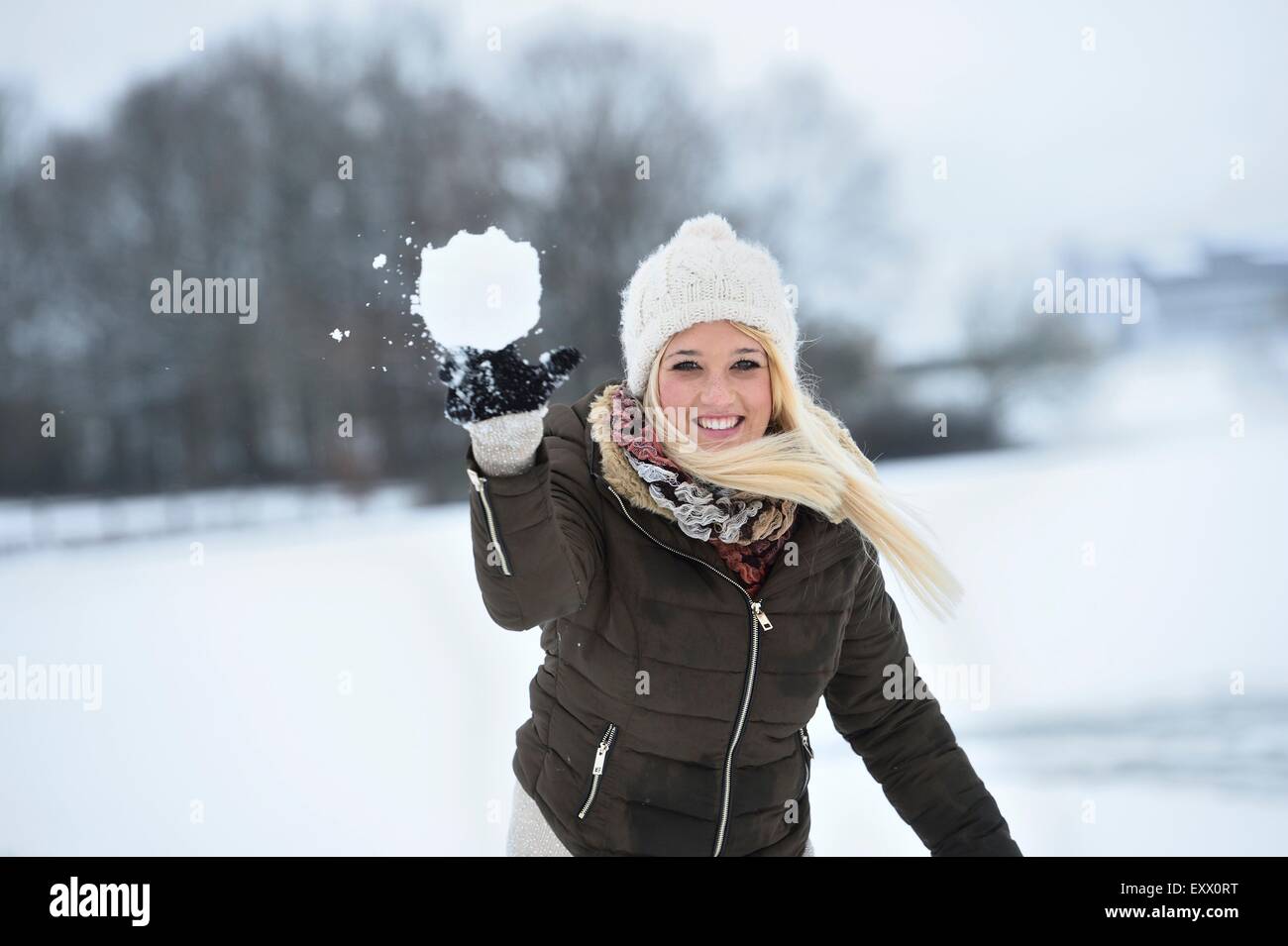 Happy young woman throwing a snowball Stock Photo - Alamy