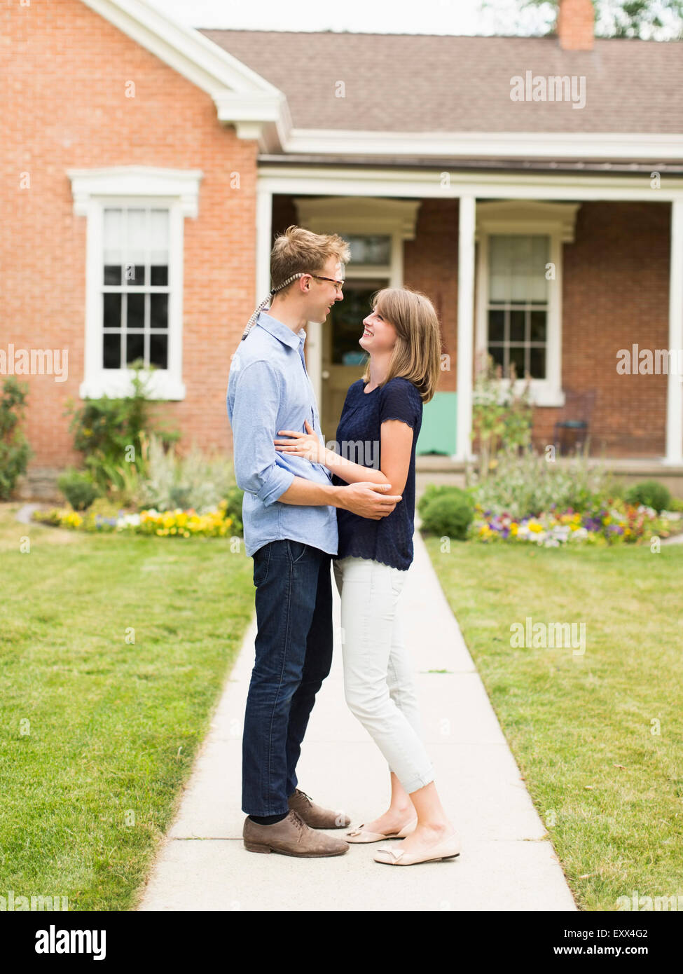 Young couple standing on footpath in front of house Stock Photo - Alamy