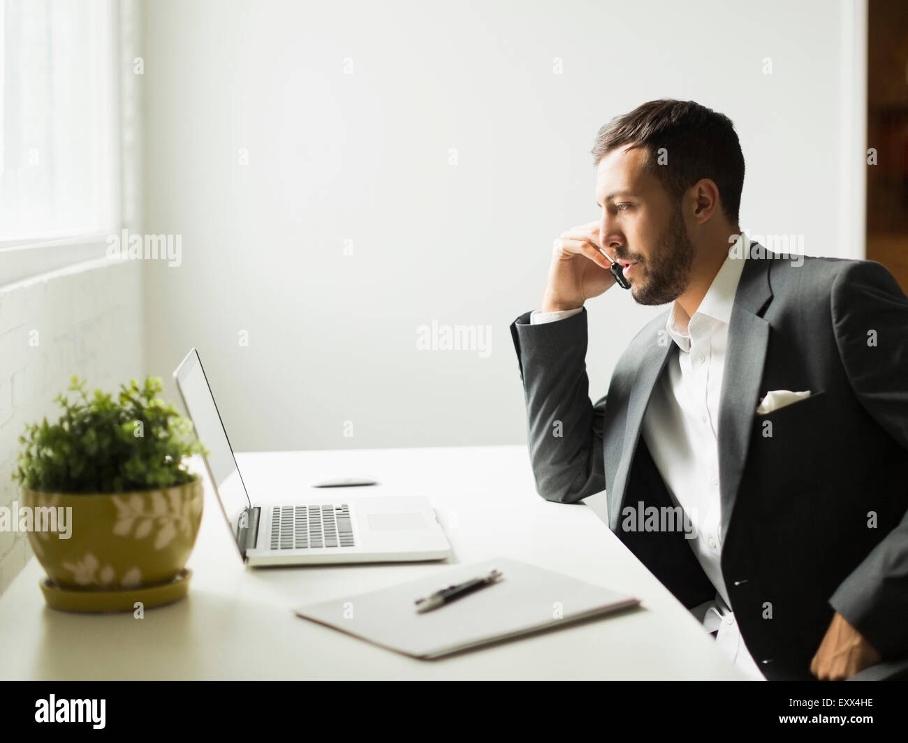 Young man sitting at desk and looking at laptop Stock Photo - Alamy
