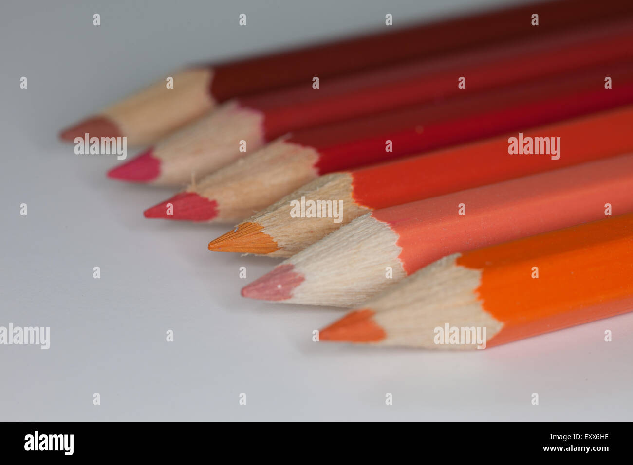 Stacked pencils displaying warm color's against a white background with ...