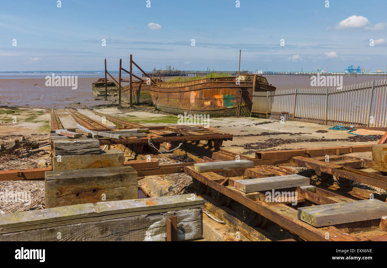 Disused ship yard with derelict iron ships and rusting winch flanked by ...