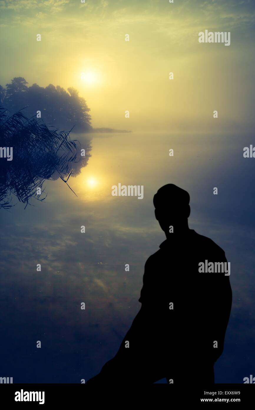 Man watching a sunrise over lake. Human silhouette. Photo with vintage ...