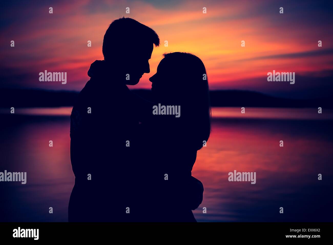 Silhouettes of hugging couple against the sunset sky. Photo with ...