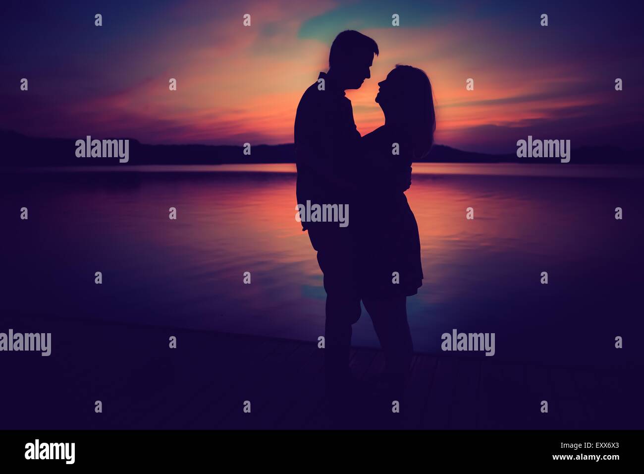 Silhouettes of hugging couple against the sunset sky. Photo with ...