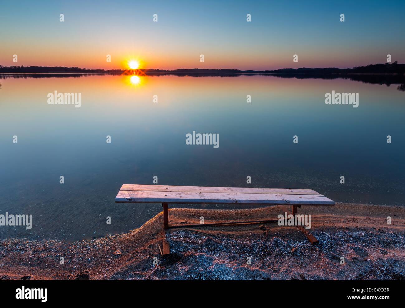 Bench on lake shore at sunset. Beautiful landscape photographed in ...