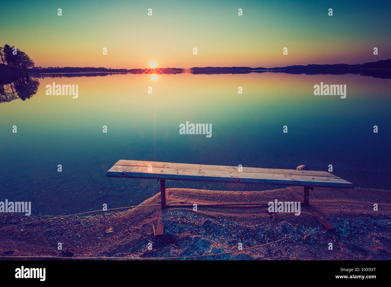 Bench on lake shore at sunset. Beautiful landscape photographed in ...
