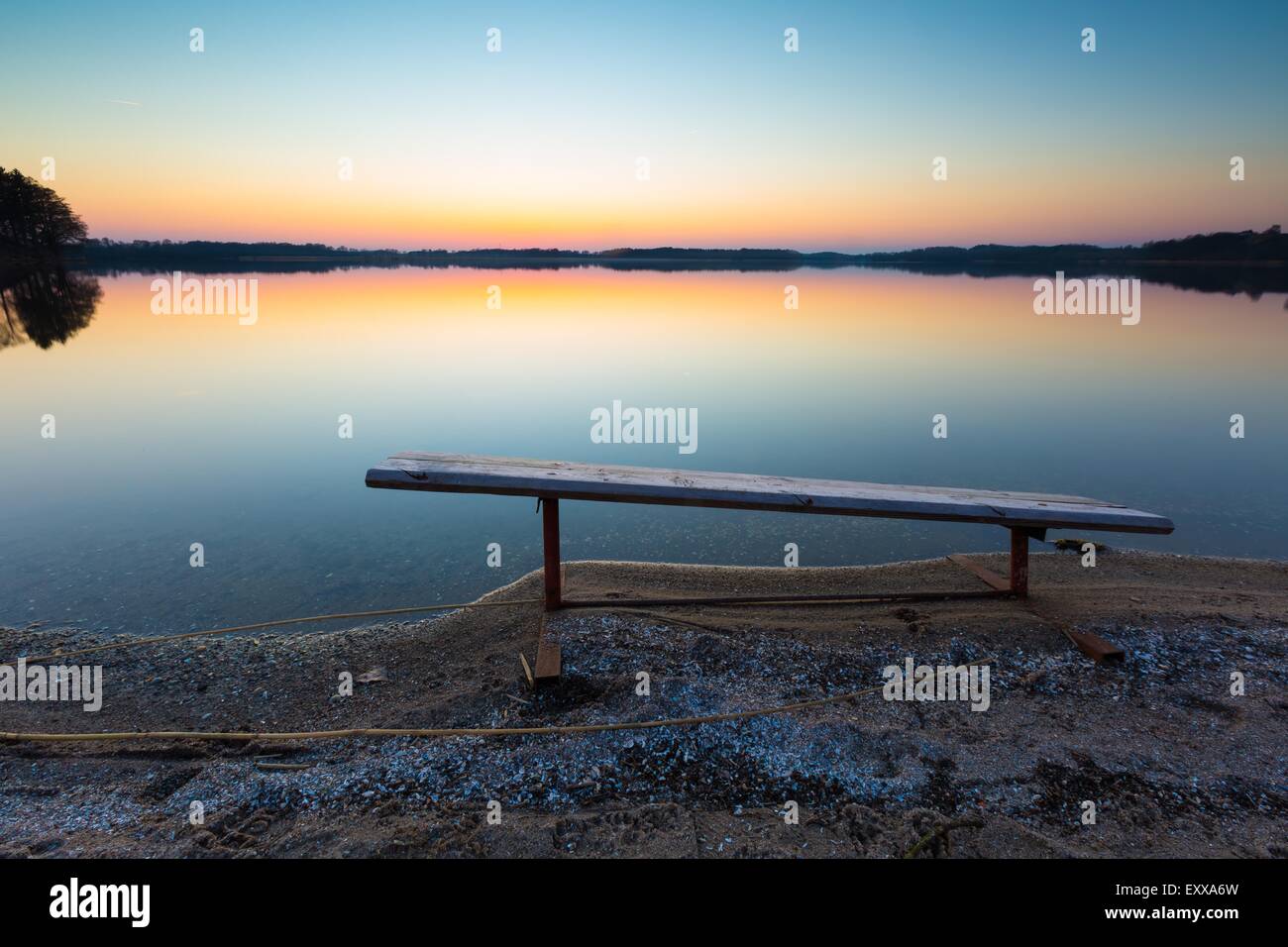 Bench on lake shore at sunset. Beautiful landscape photographed in ...