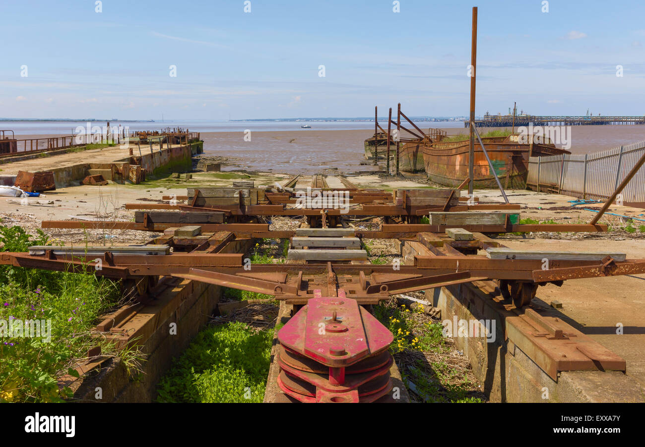 Disused ship yard with derelict iron ships and rusting winch flanked by ...