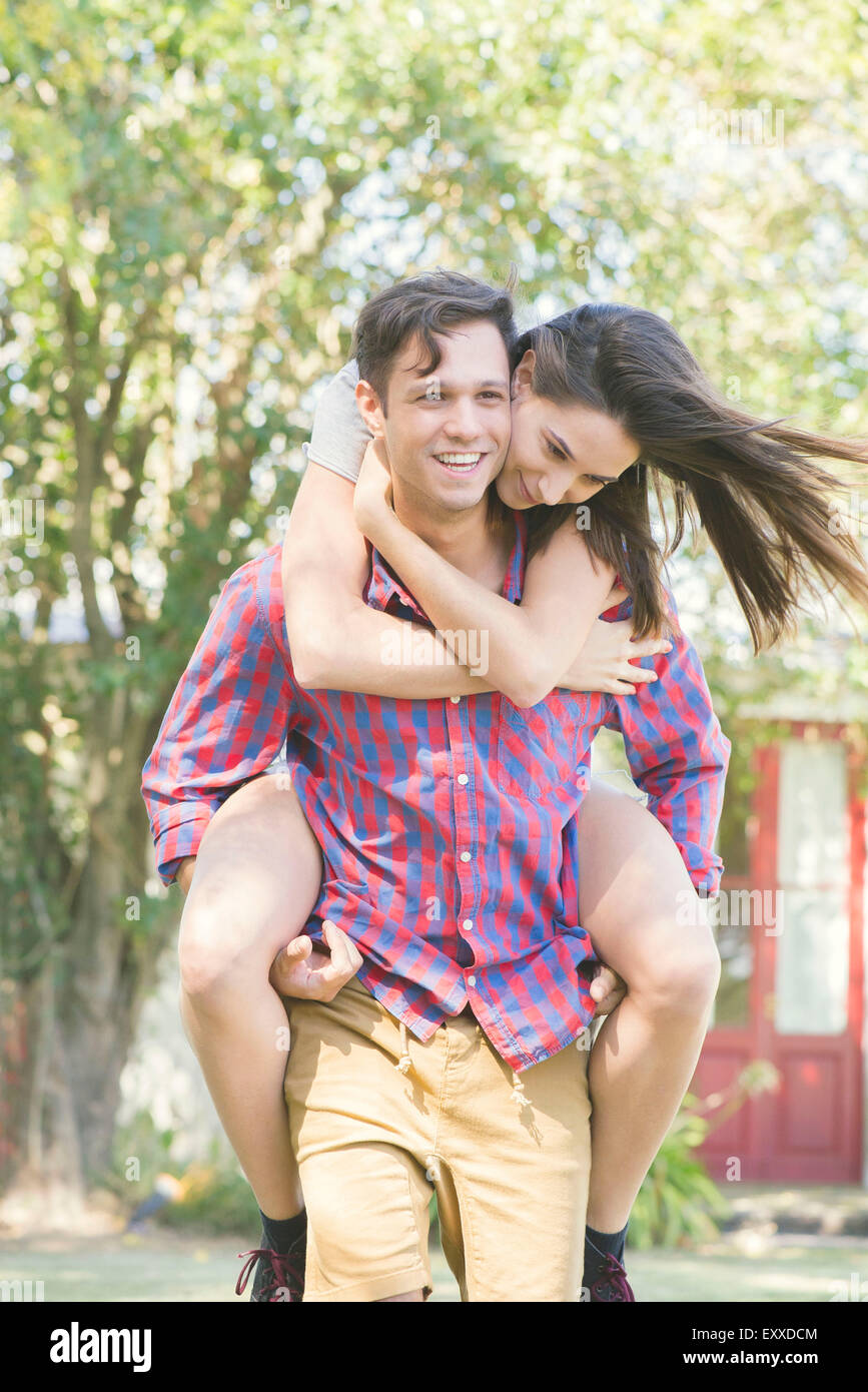 Couple together outdoors, man giving woman a piggyback ride Stock Photo ...