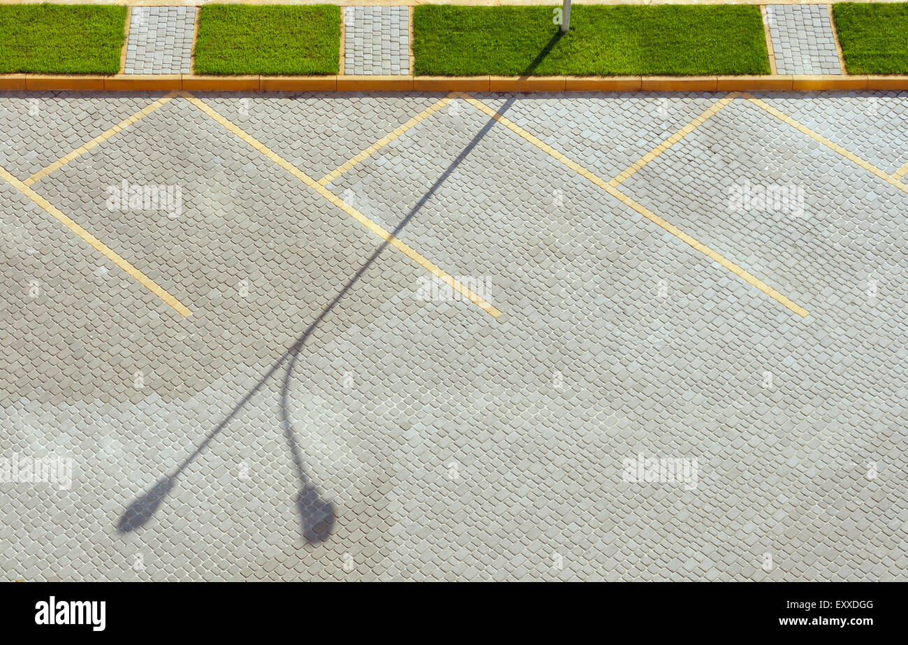 Pavement empty parking lot with green grass and shadow of street lamp ...