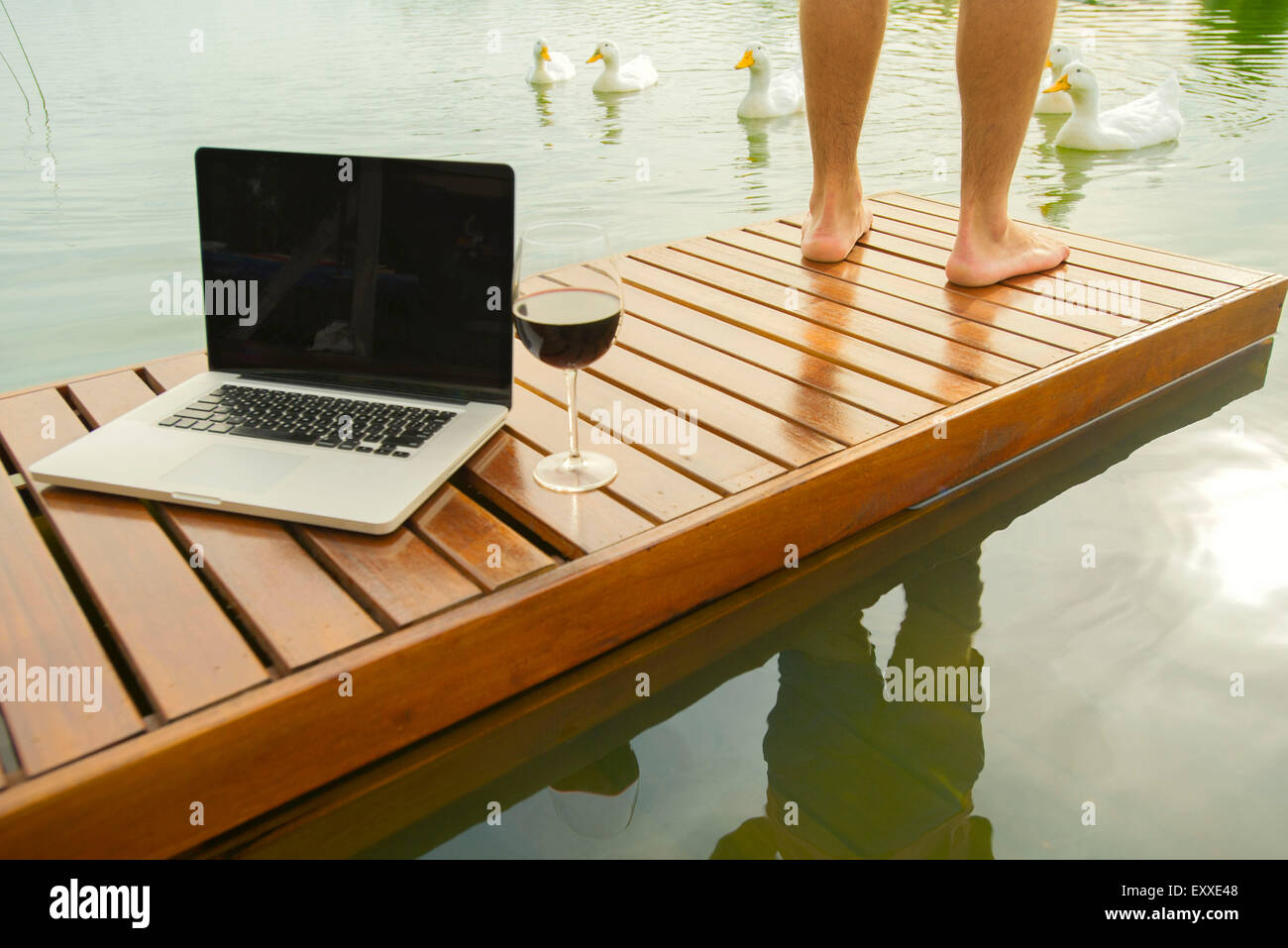 Man standing beside laptop computer and wine glass on lake pier Stock ...
